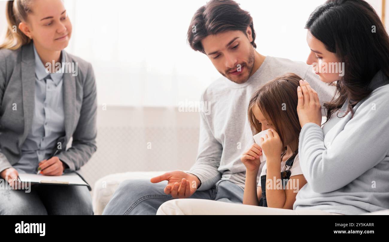 Caring parents comforting their little crying daughter at children ...