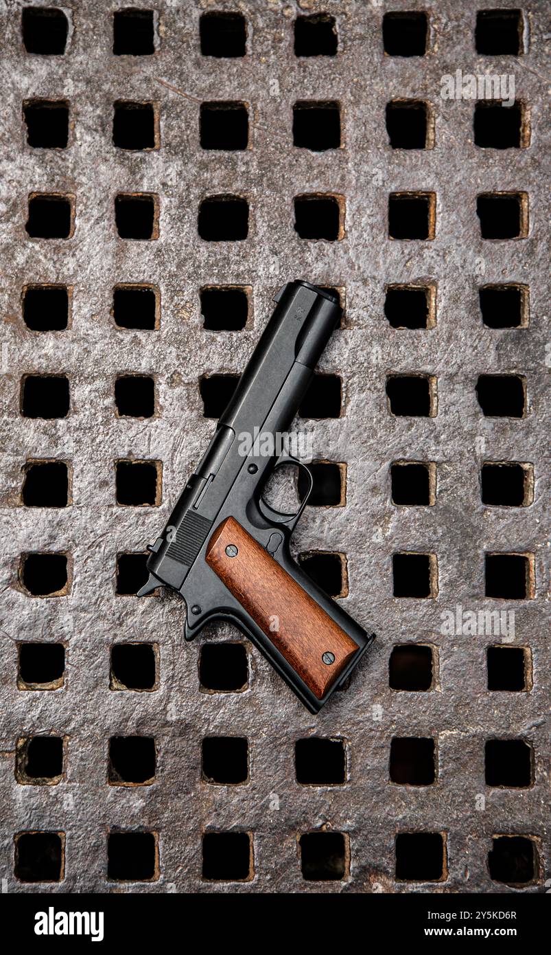 Black handgun with wooden grip resting on a rusted, industrial metal ...