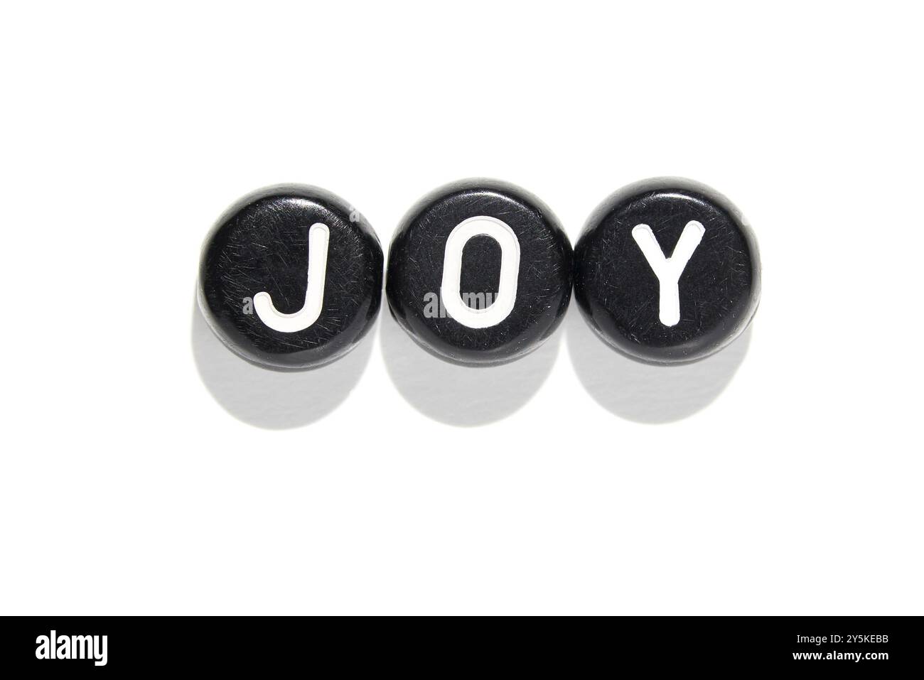 Black circular objects spelling joy on white background for positive ...