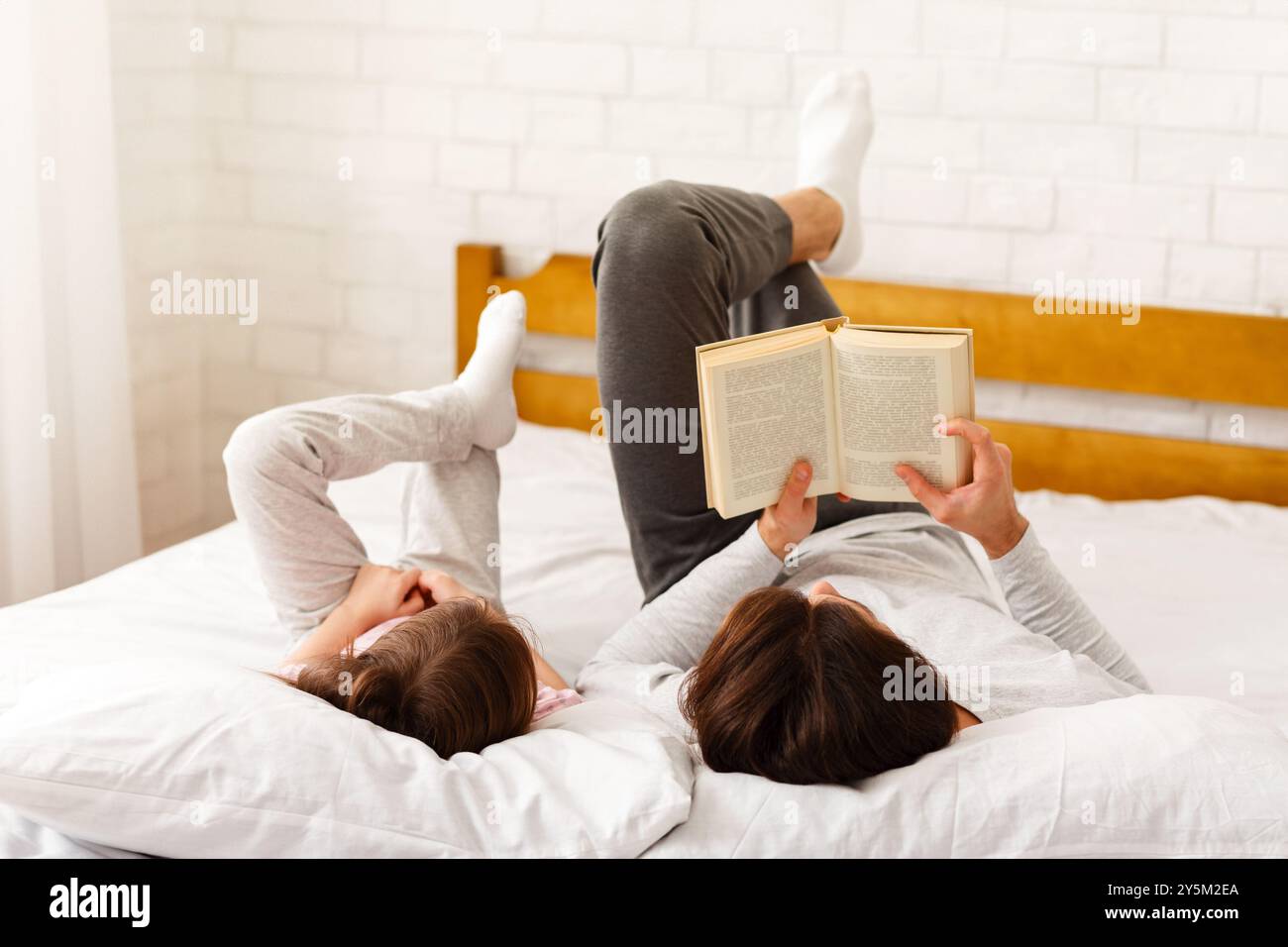 Father and daughter reading book together on weekend Stock Photo - Alamy