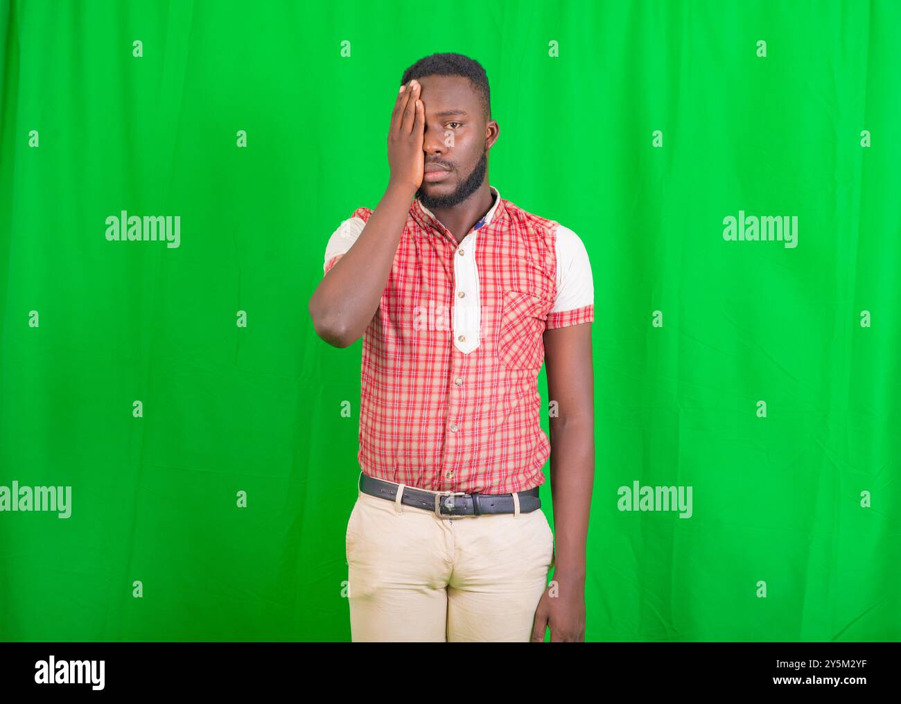 portrait of a handsome young man standing against green background and ...