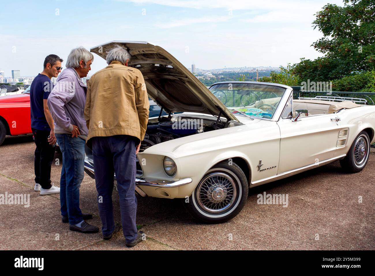 An outdoor exhibition of vintage cars. Three gentlemen checking out the ...