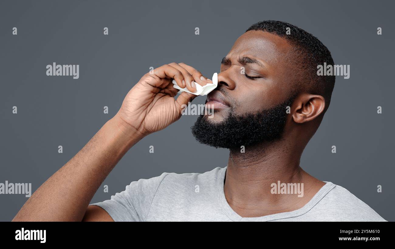 Man touching his nose with napkin, bleeding Stock Photo - Alamy