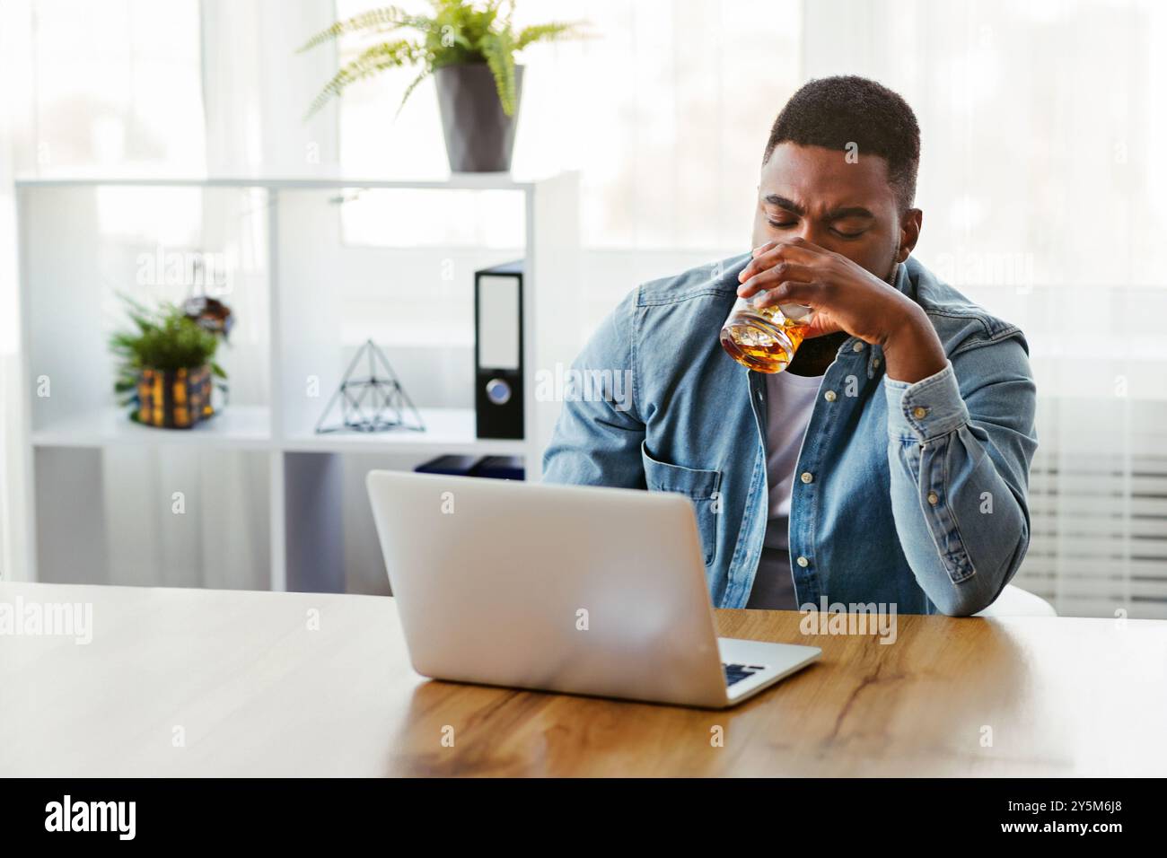 Tired african american employee drinking alcohol at workplace Stock ...