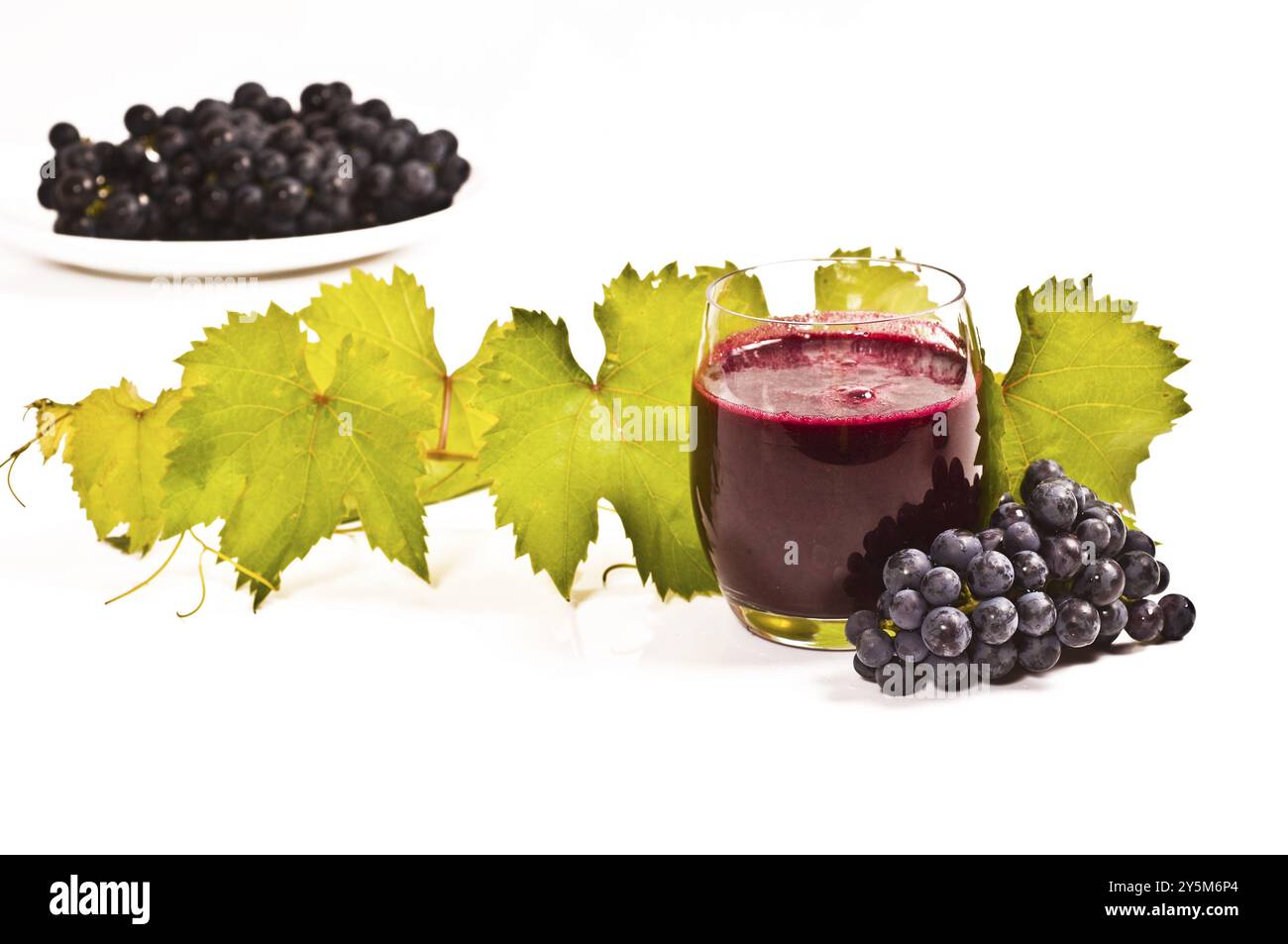 Freshly pressed red grape juice with vine leaves on a white background ...