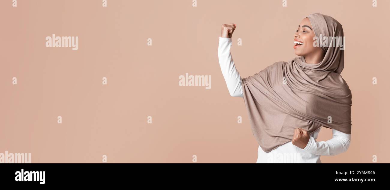 Afro muslim girl in hijab celebrating success, raising hands with ...