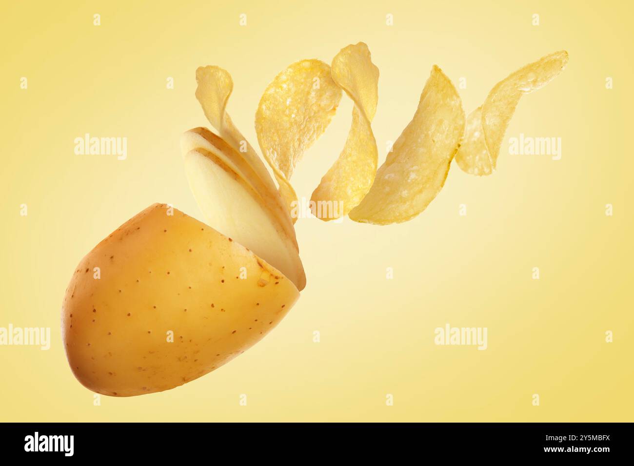 Raw potato turning into tasty crispy chips in air on yellow background ...