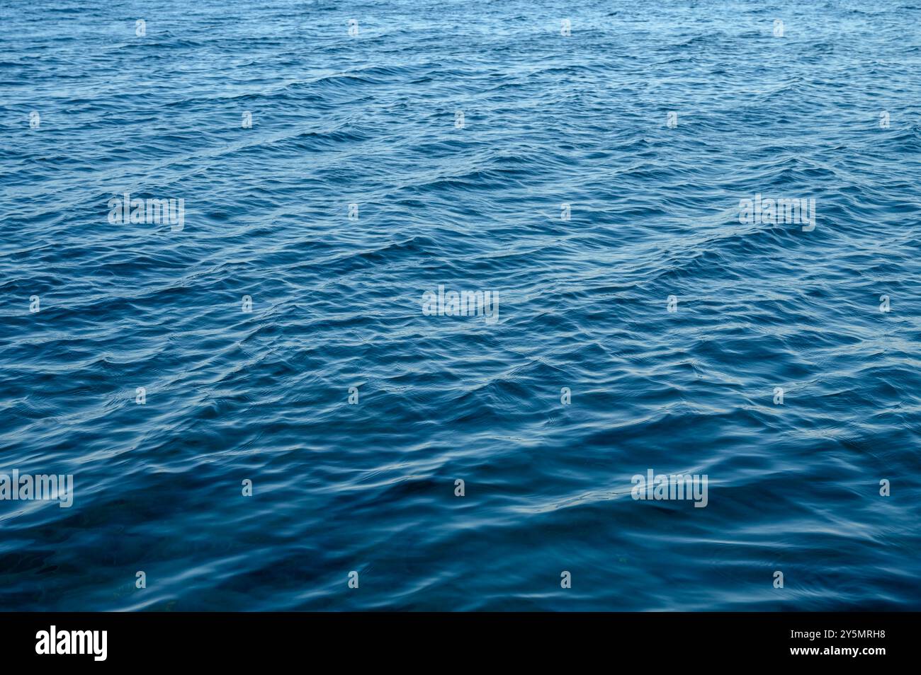 Blue water surface viewed from above in outdoor sea, sun reflection ...