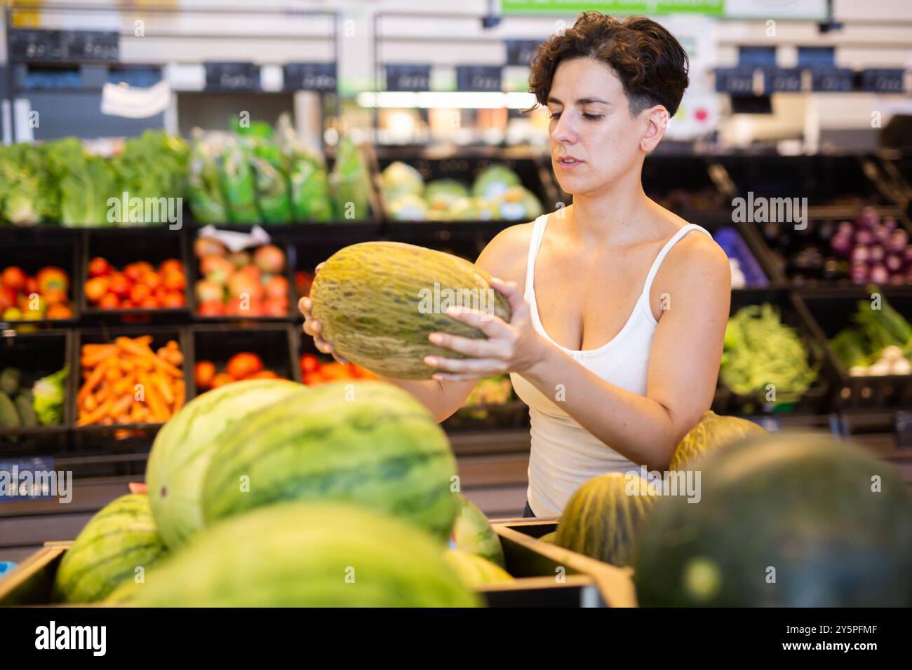 Woman choosing melon in grocery store Stock Photo - Alamy