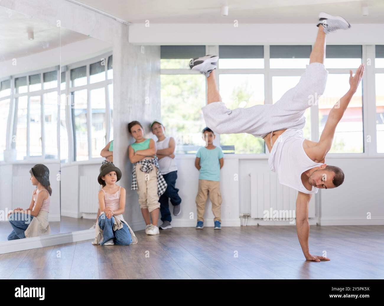 Young breakdancer demonstrating dance moves to group of tweens in ...