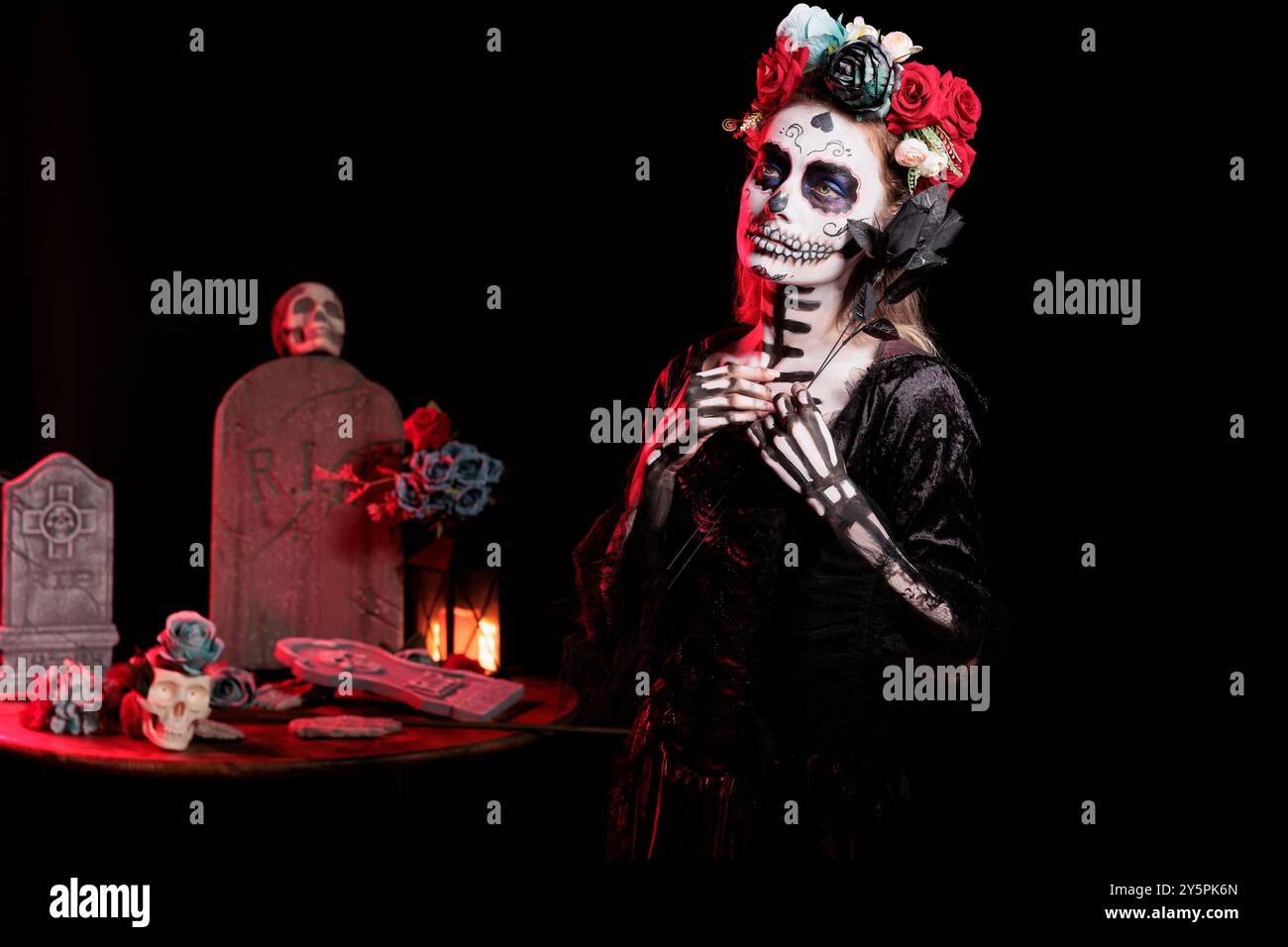 Woman holding black rose participating at Dia de los Muertos party ...