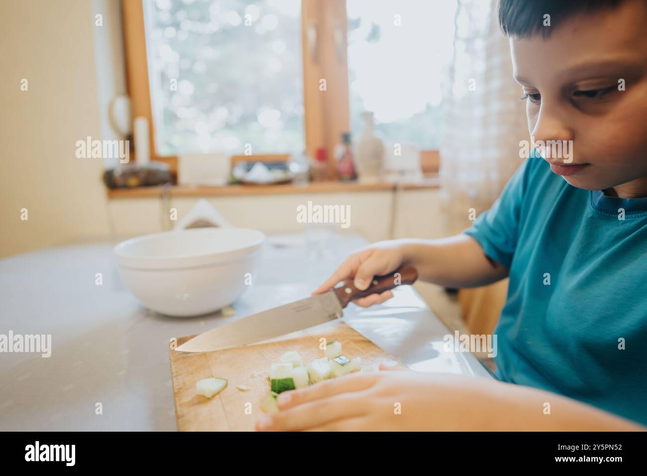 Young boy learning to chop vegetables in the kitchen Stock Photo - Alamy
