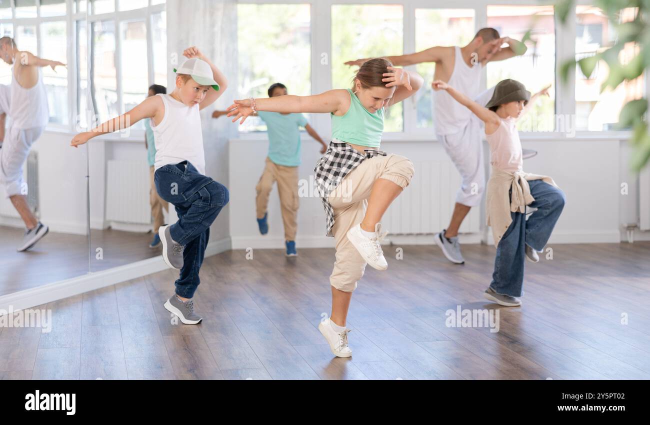 Group of teen children participating hip hop dance in class, following ...