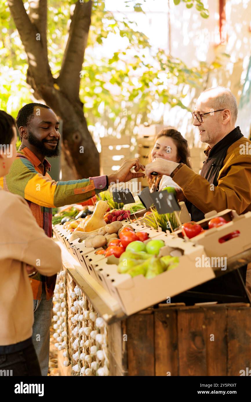 Black guy tasting freshly harvested produce at farmers market, old man ...