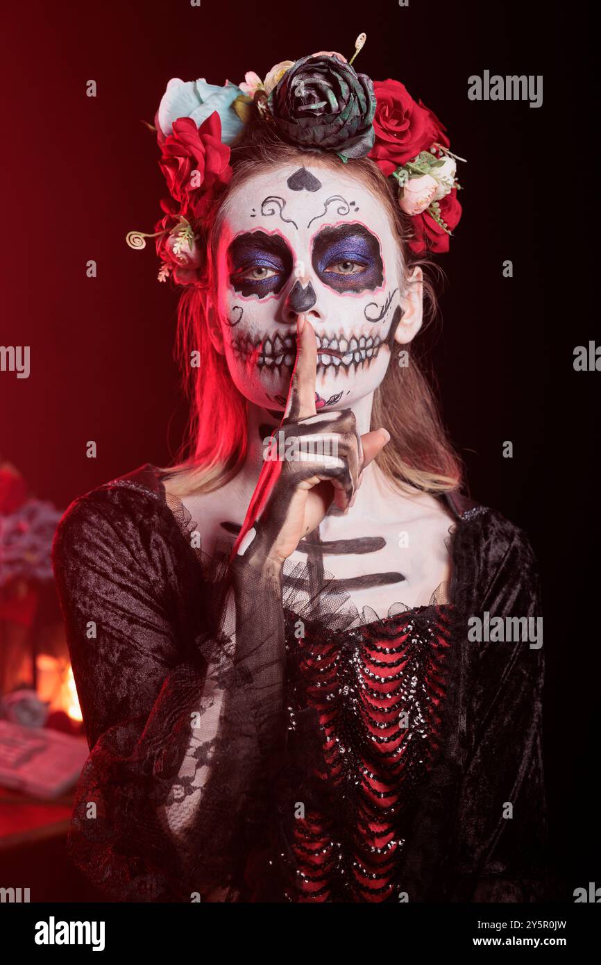 Woman doing shush finger gesture in graveyard, celebrating Day of the ...