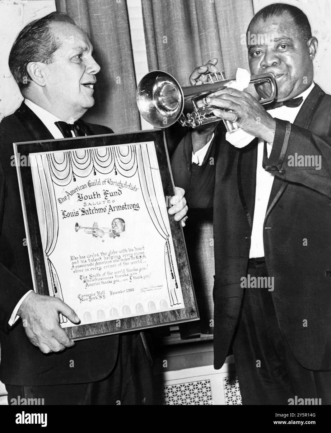 Louis Armstrong plays trumpet while Joey Adams, president of the ...