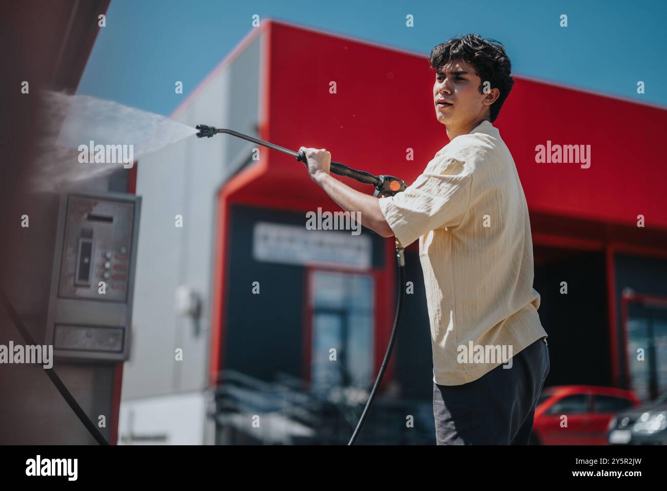 Young man using pressure washer at car wash station Stock Photo - Alamy