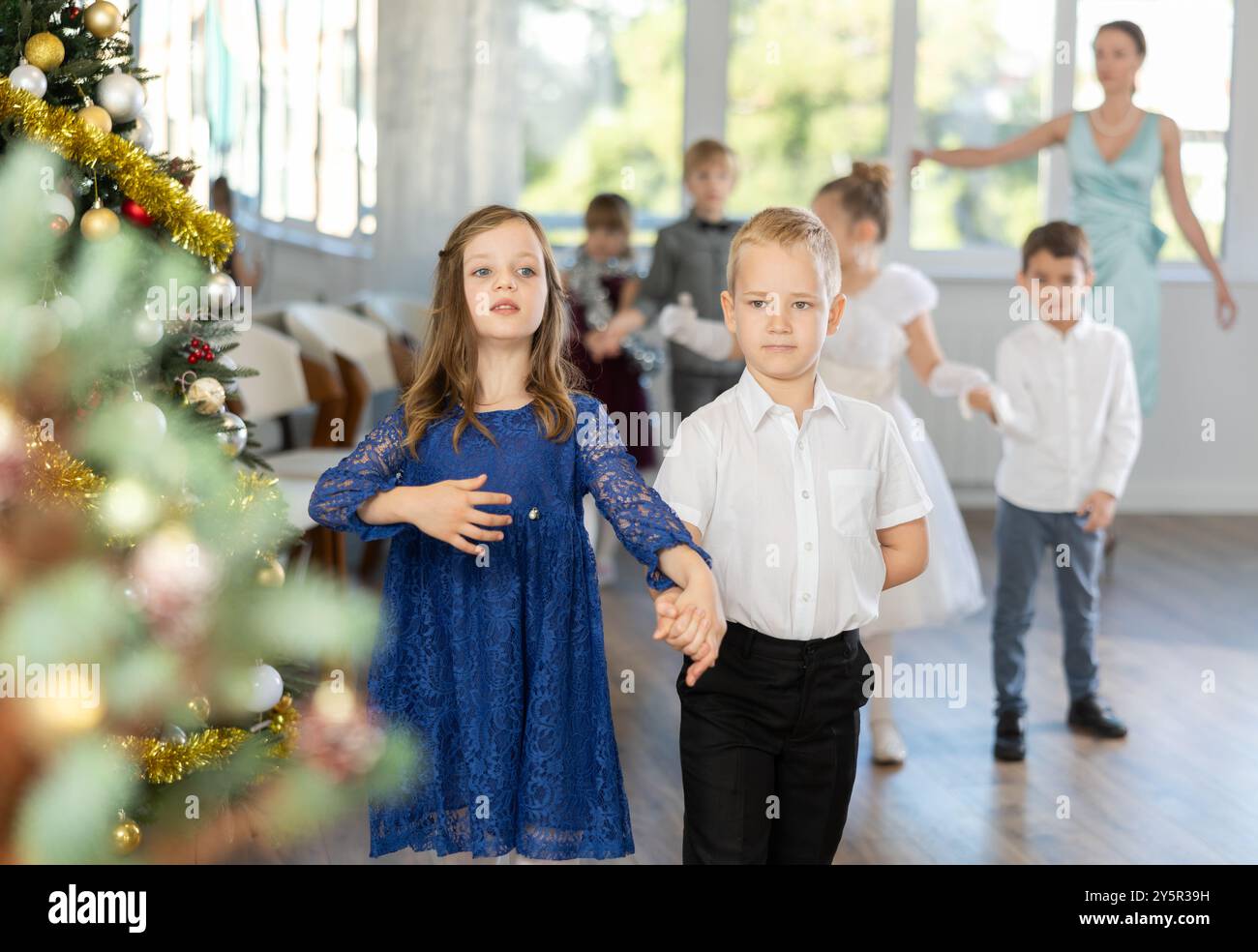 Little children standing in pairs in school-hall decorated with Xmas ...