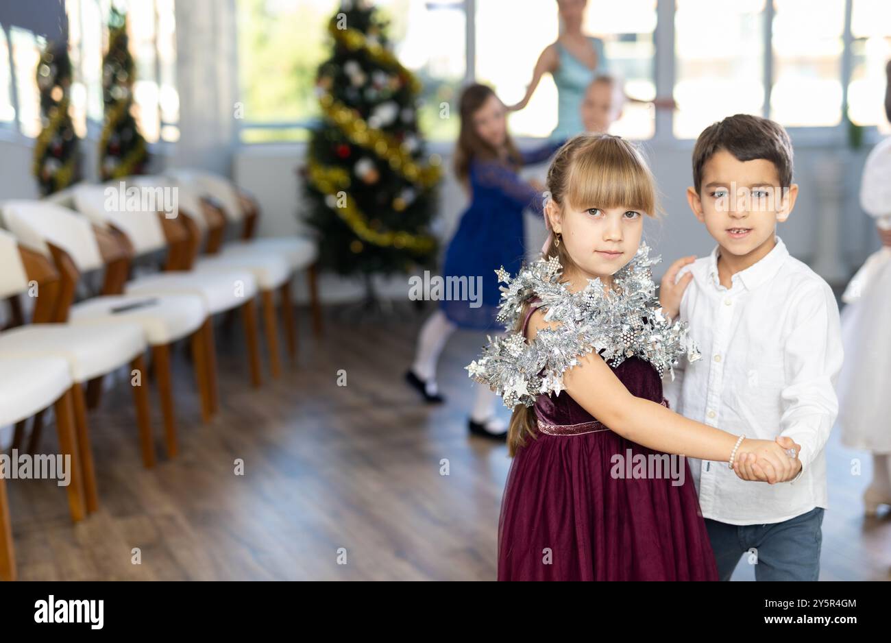 Christmas ball - group of preteen children in festive clothes dances a foxtrot near New Year ...