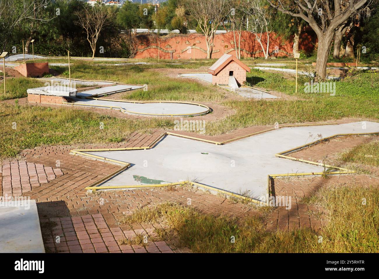 An old, star-shaped obstacle is visible on a worn mini golf course ...
