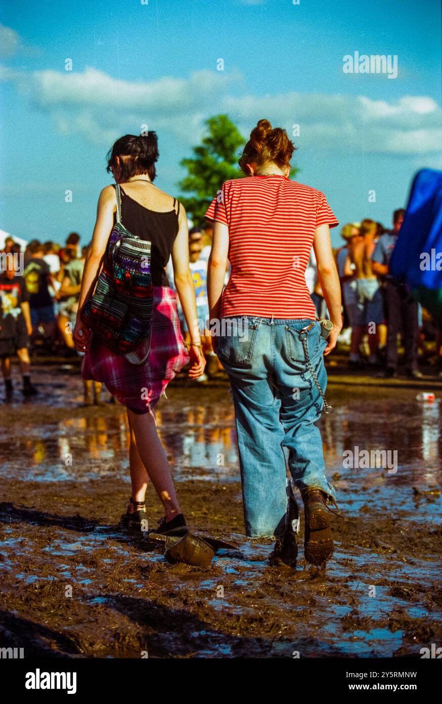 Two friends wade through the muddy terrain of Lollapalooza in Kansas ...
