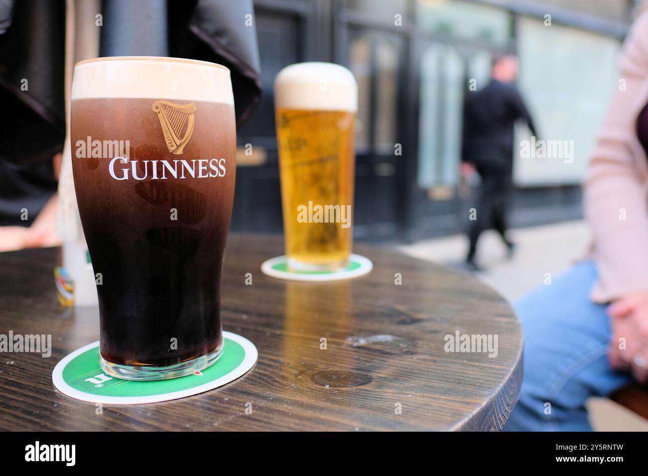 A branded glass of Guinness stout beer with creamy froth head at the ...
