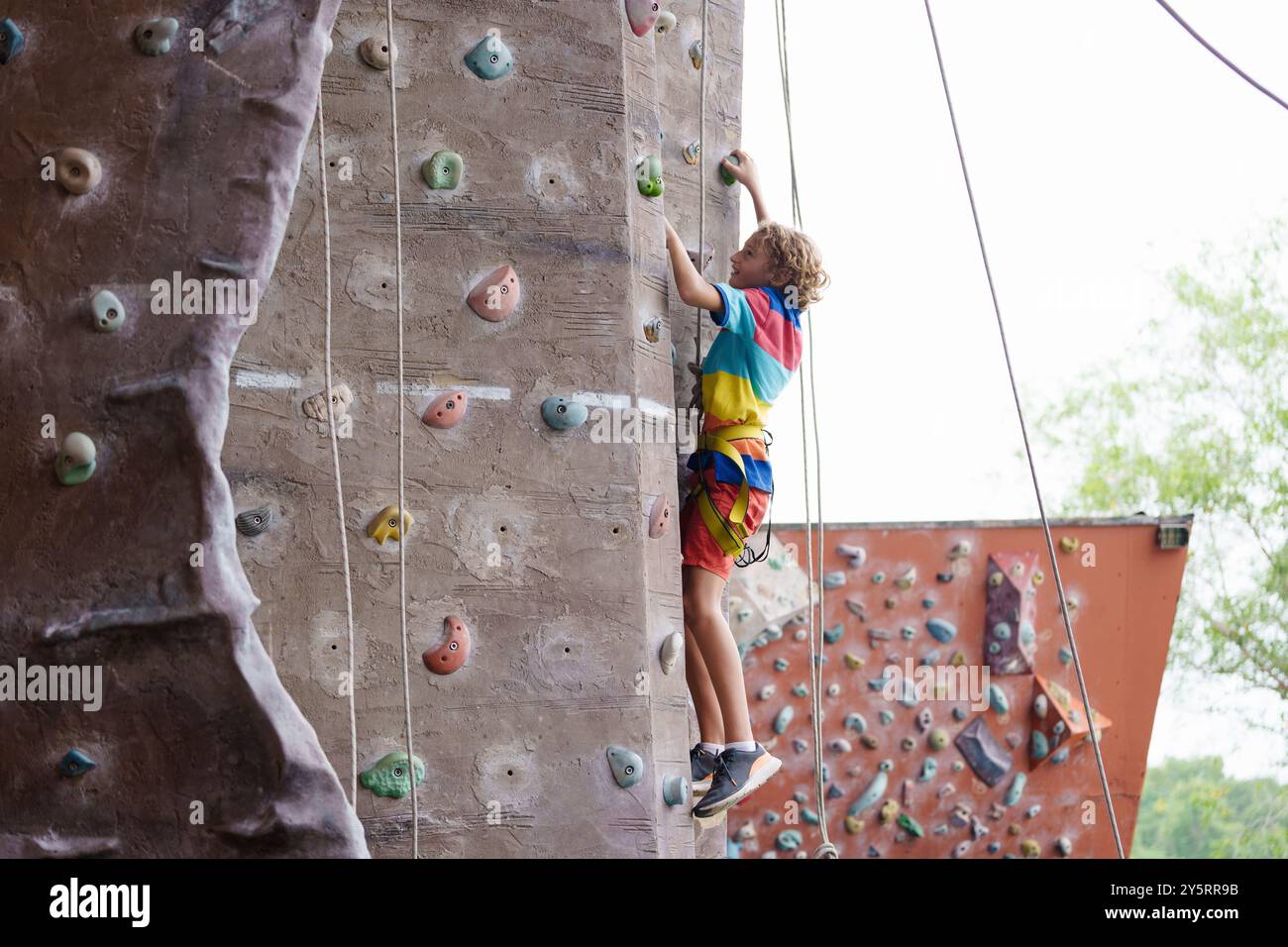 Child on rock climbing course. School boy bouldering. Extreme sport for ...