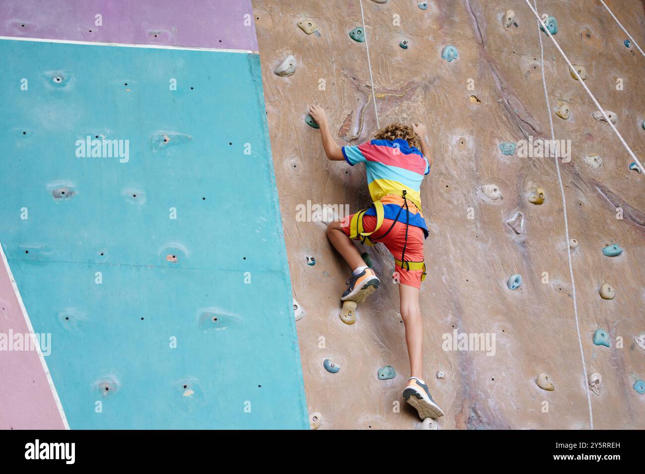Child on rock climbing course. School boy bouldering. Extreme sport for ...