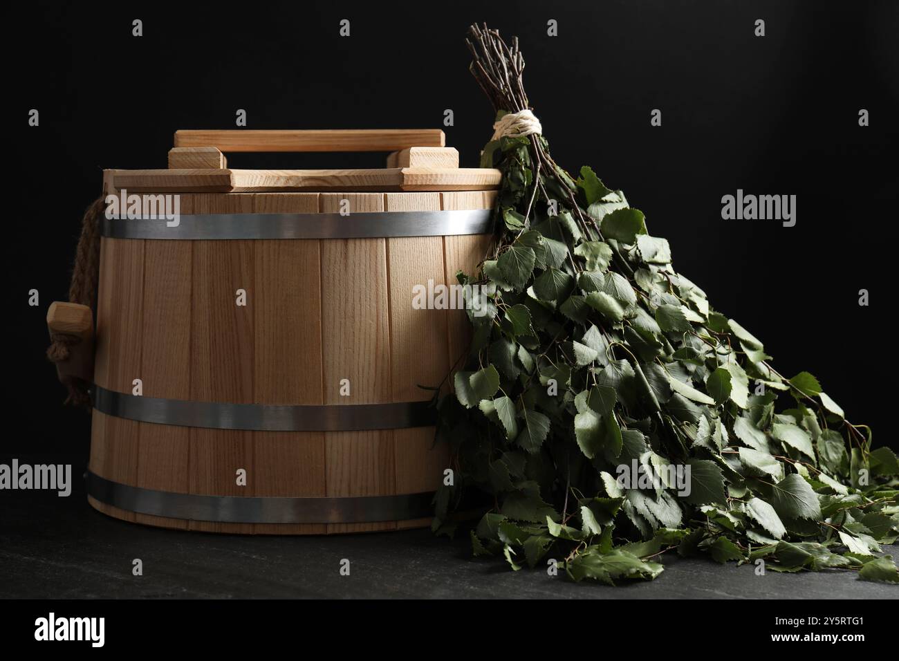 Sauna equipment. Bucket and birch whisk on black textured surface Stock ...