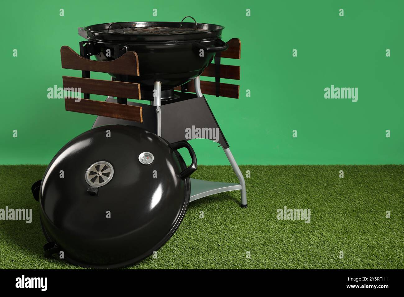One black barbeque grill on grass against green background. Space for ...