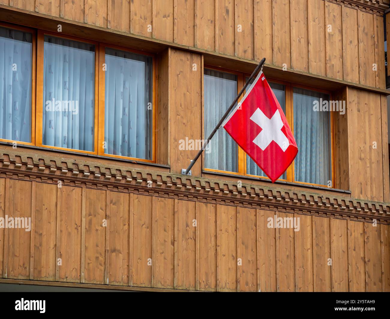 The Swiss flag is placed on the glass window of brown wooden house ...