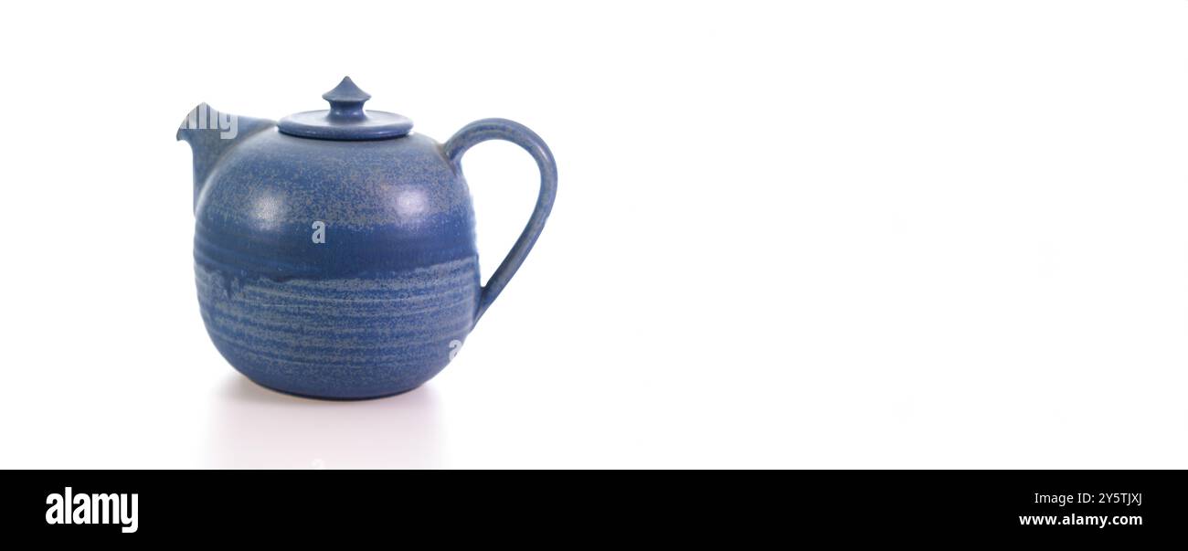 A blue ceramic teapot with a round body and smooth finish stands ...