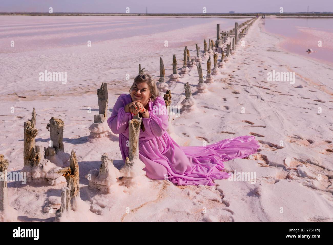 Woman Pink Lake Salt Posts - A woman in a pink dress kneels in front of ...