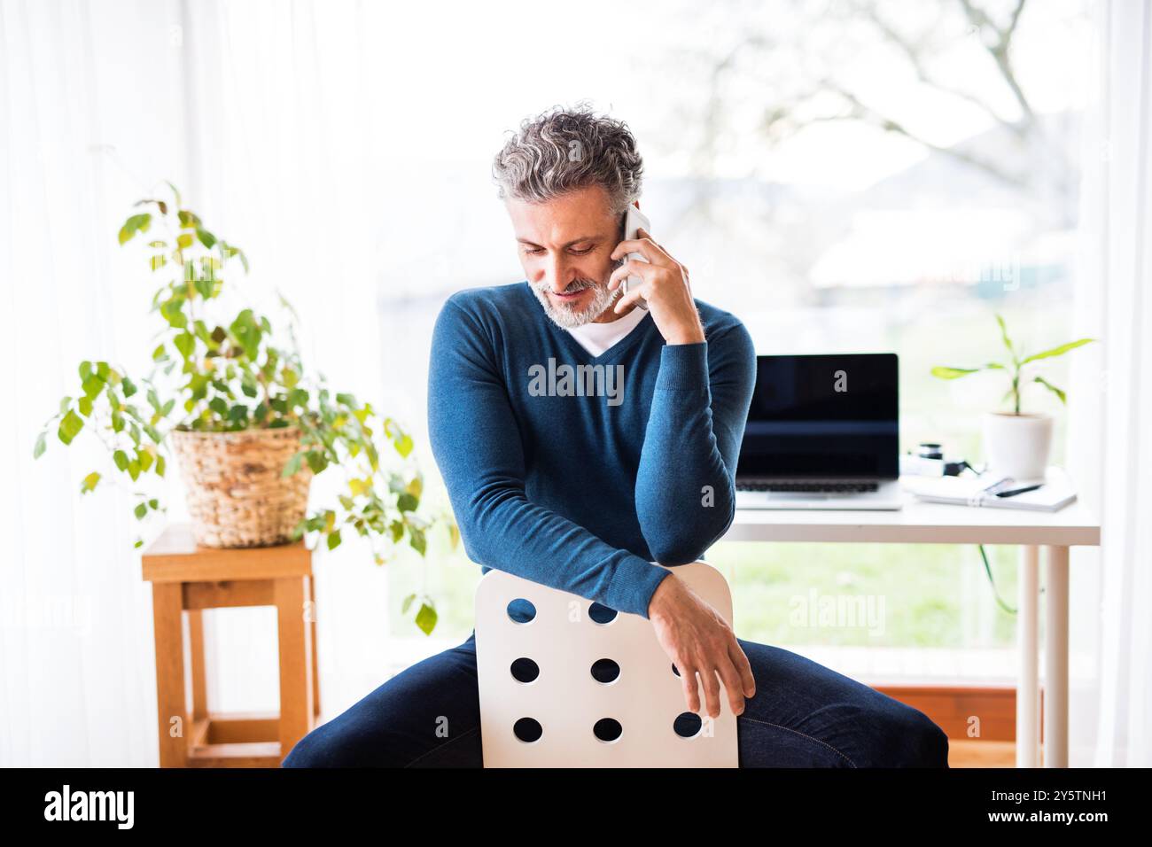 Man sitting on chair backward, making phone call. Homeoffice for ...