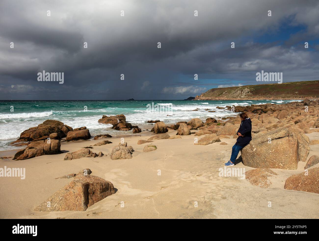 Woman watching an approaching storm on a beach, Sennen Cove, Cornwall ...
