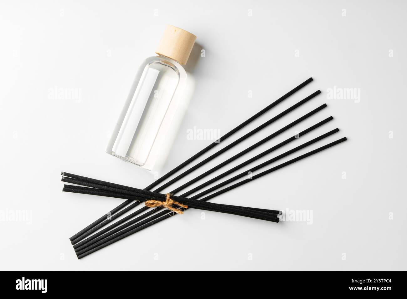 A minimalist display of essential oil and black diffuser sticks on a ...