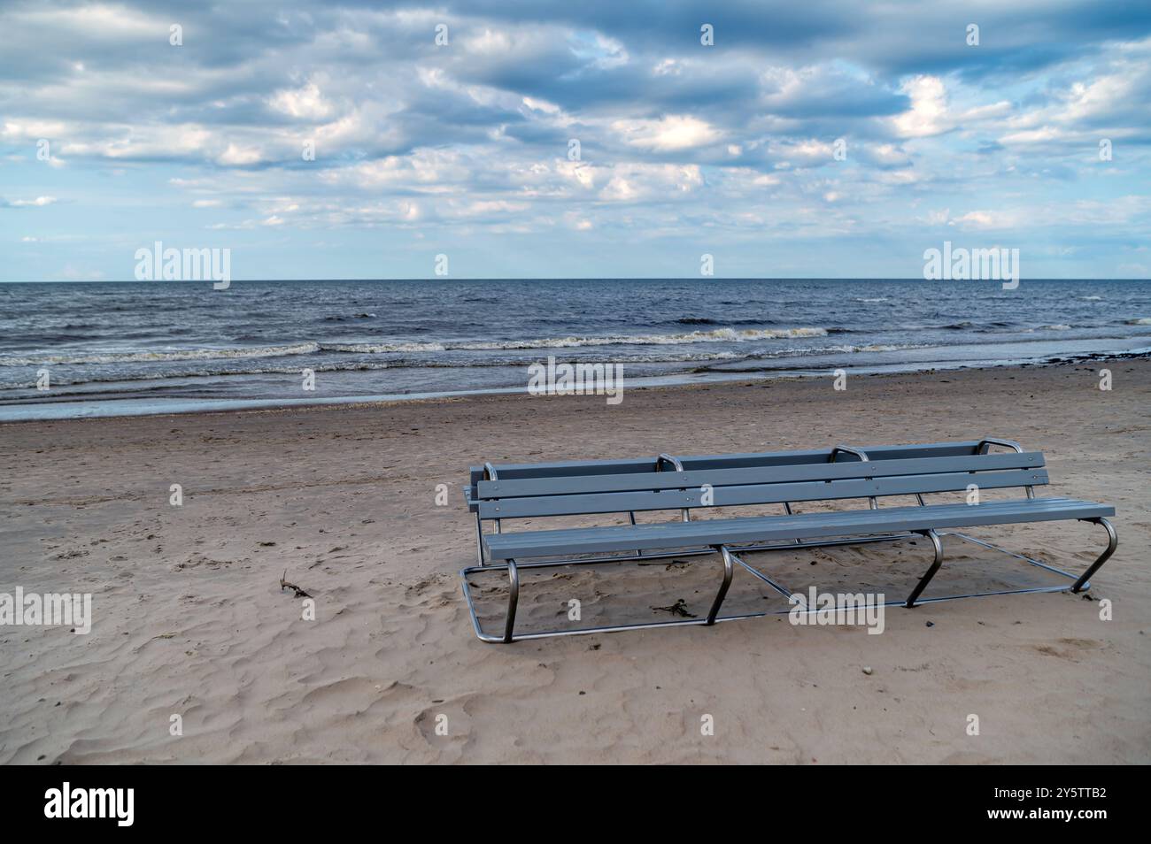 A bench faces the ocean, surrounded by soft sand and gentle waves Stock ...