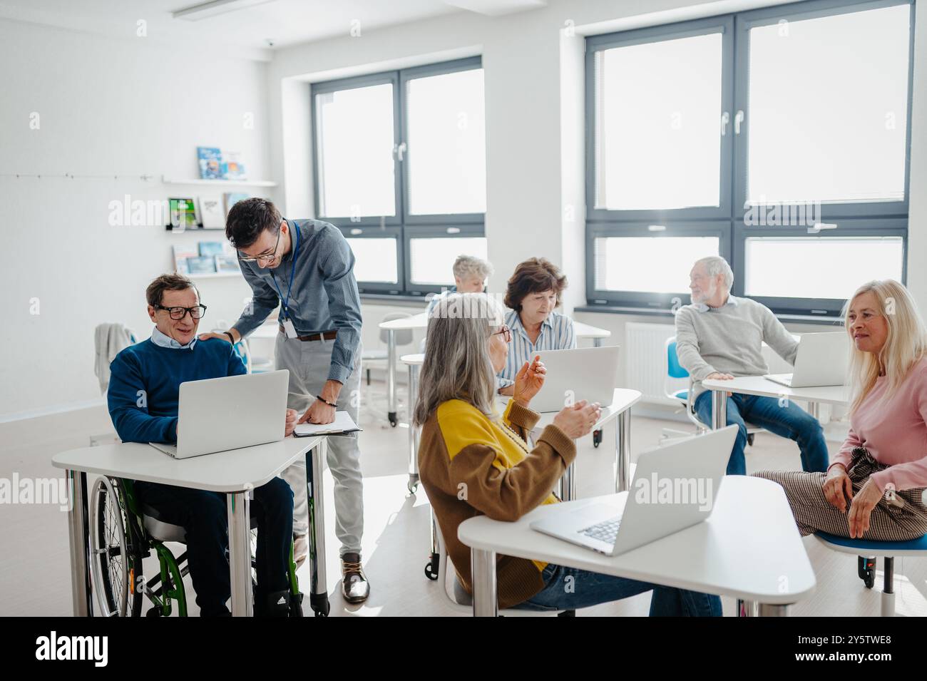 Teacher explaining senior students how to work with laptop and internet ...
