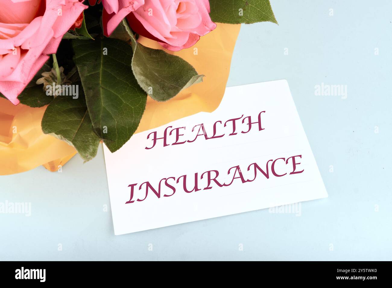 HEALTH INSURANCE words written on a white card under a bouquet of ...