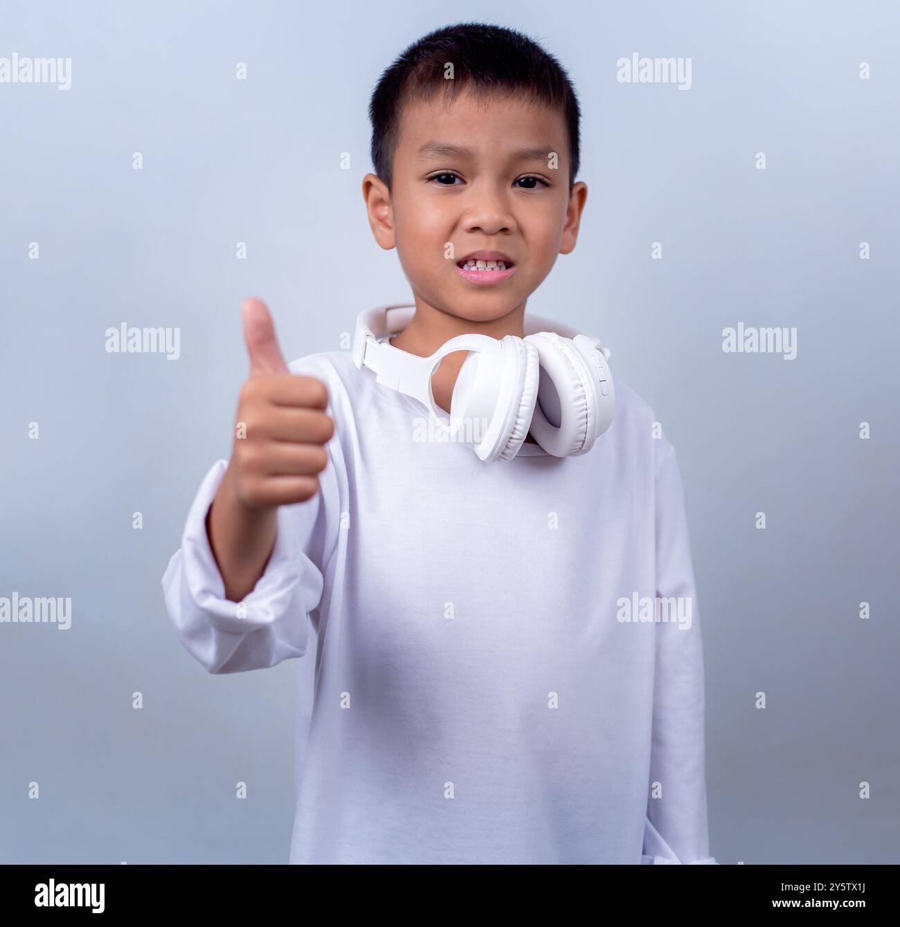 Asian boy wearing white with white headphones on his neck is giving ...