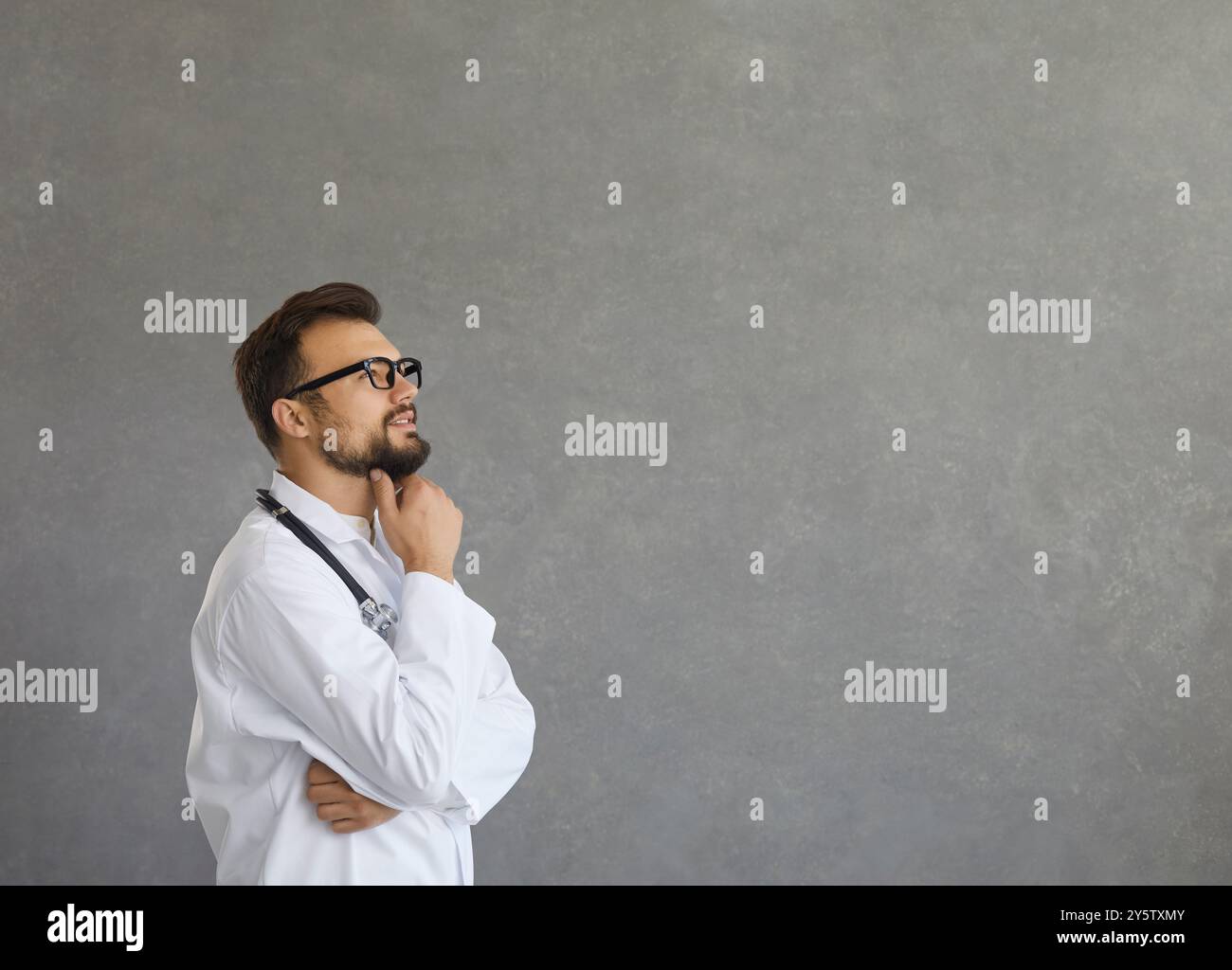Smiling dreamy male caucasian doctor in white medical uniform look in ...