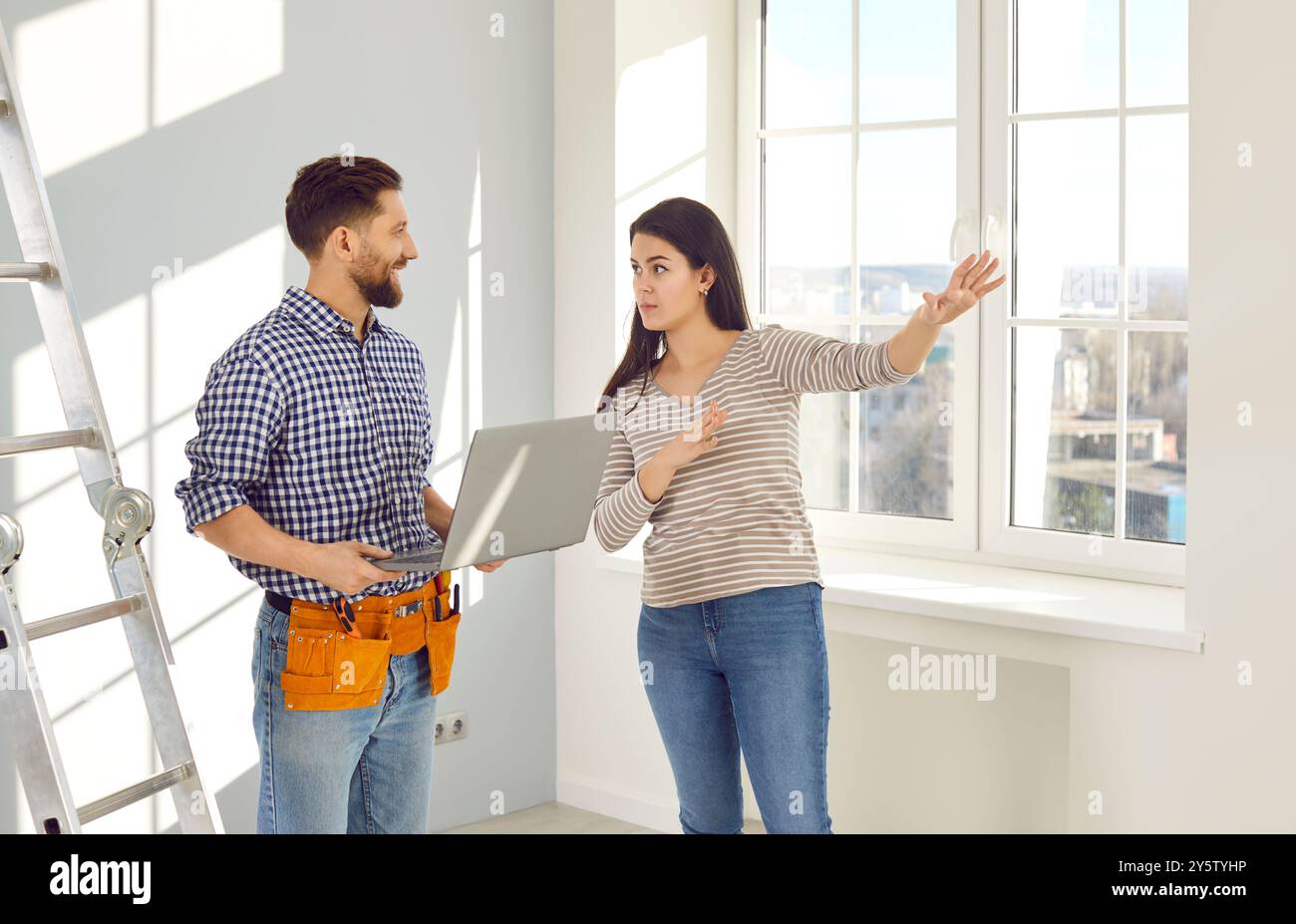 Young woman talking to a repairman who is going to repair something in ...