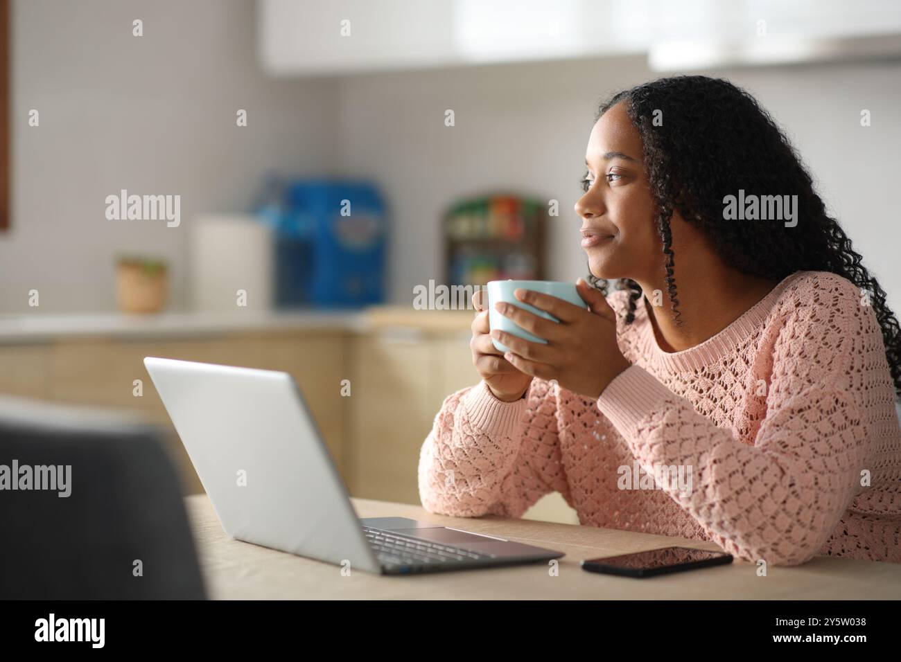 Serious black woman looking away drinking coffee sitting alone in the ...