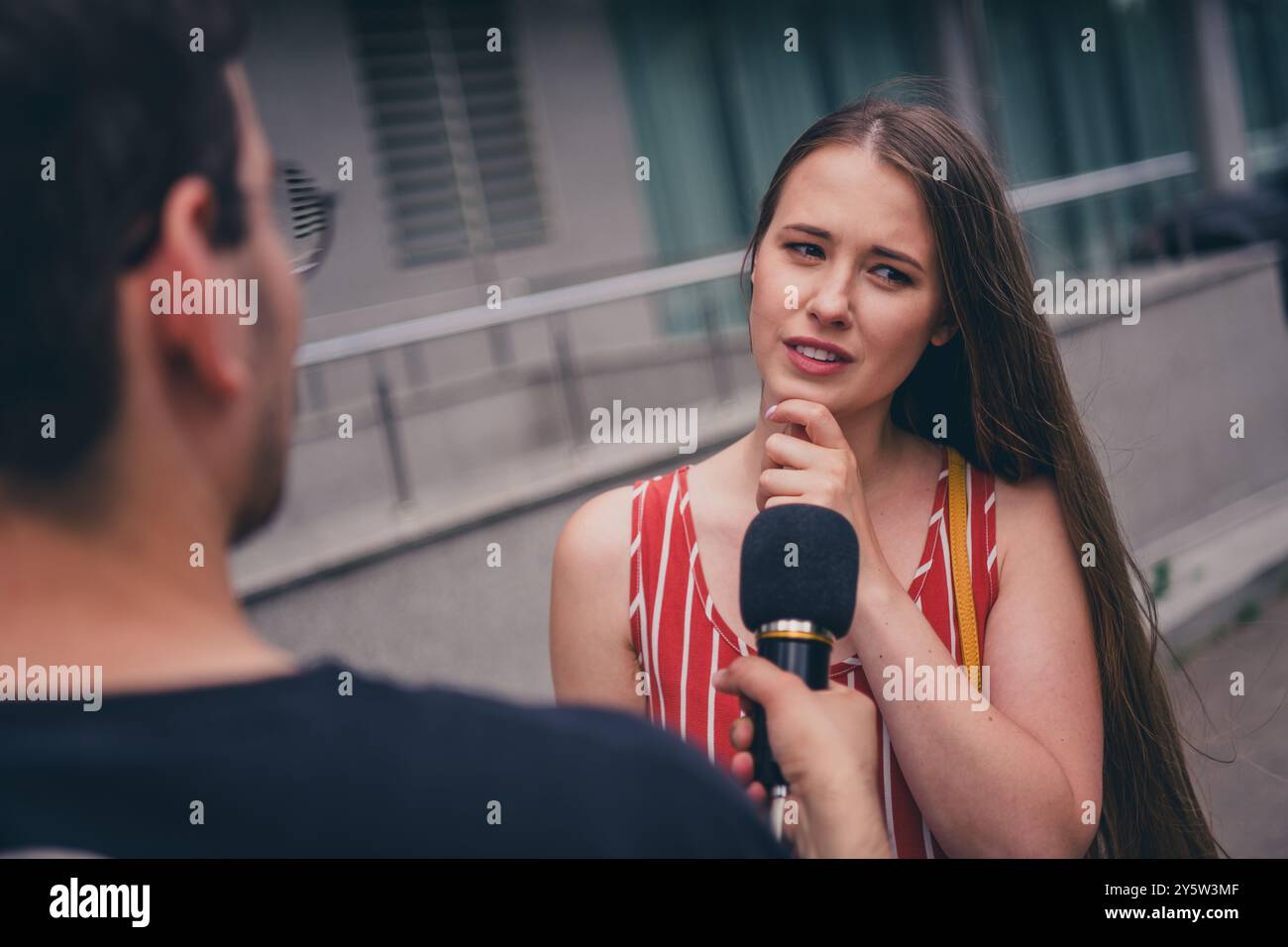 Photo of thoughtful charming girl giving interview to journalist speaking in microphone ...