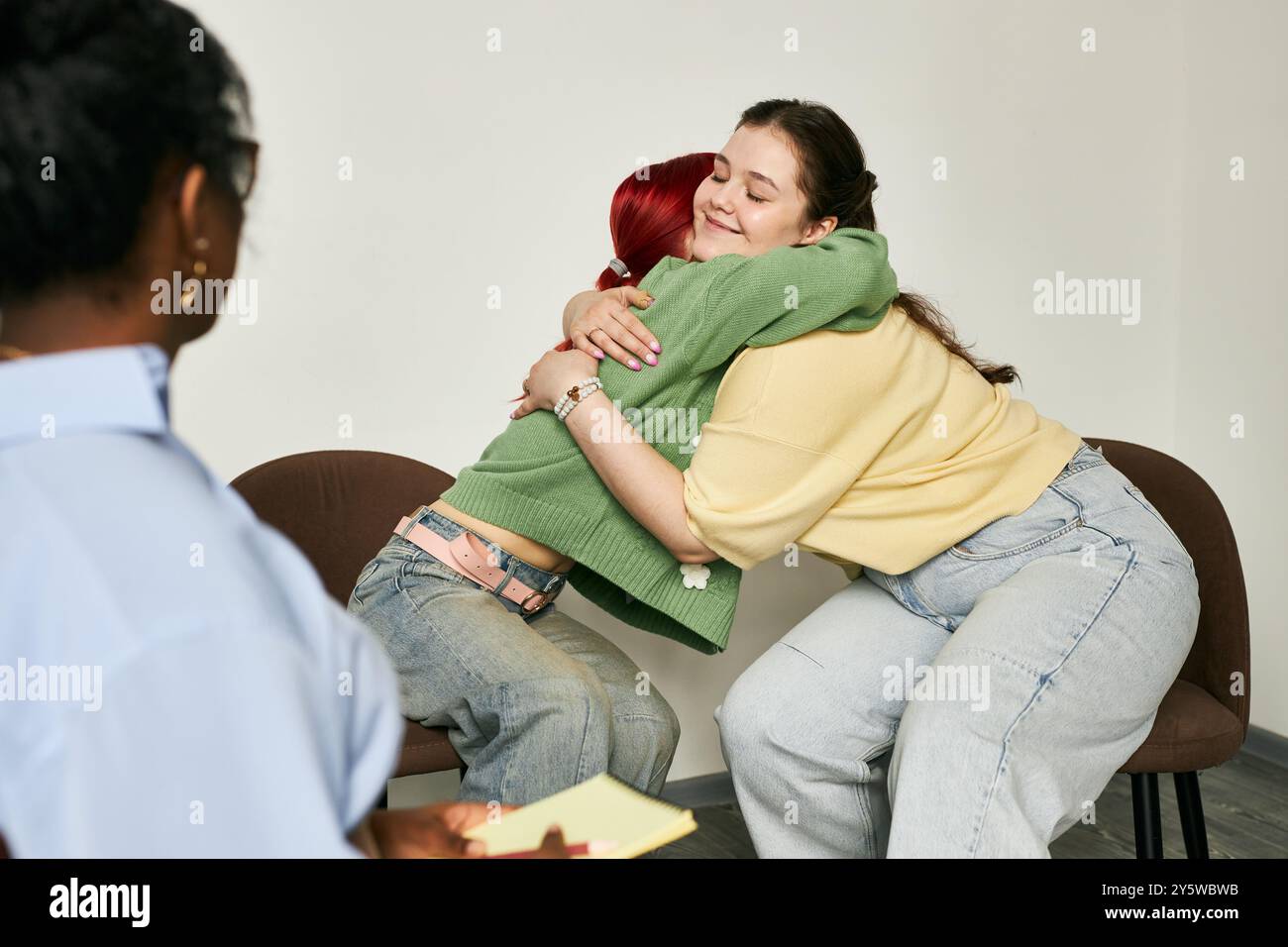 Two women embracing warmly in therapy session with third person ...