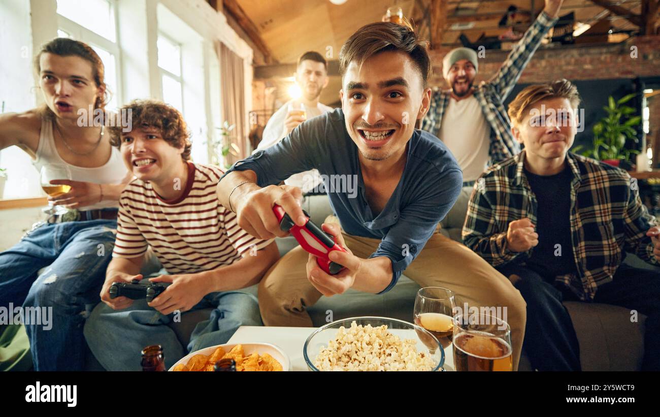 Group of friends leans in close to their screens, controllers in hand ...