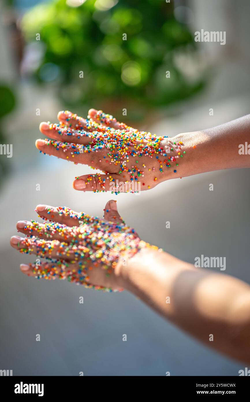 Sticky female hands in colorful sprinkles for cupcakes, donuts, cakes ...