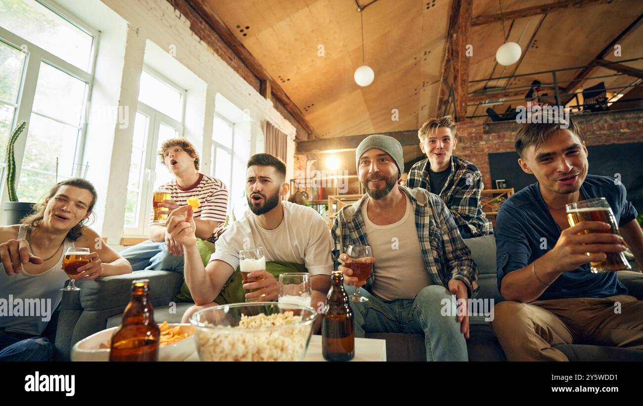 Mid-game intensity, while group of friends sitting on couch in living ...