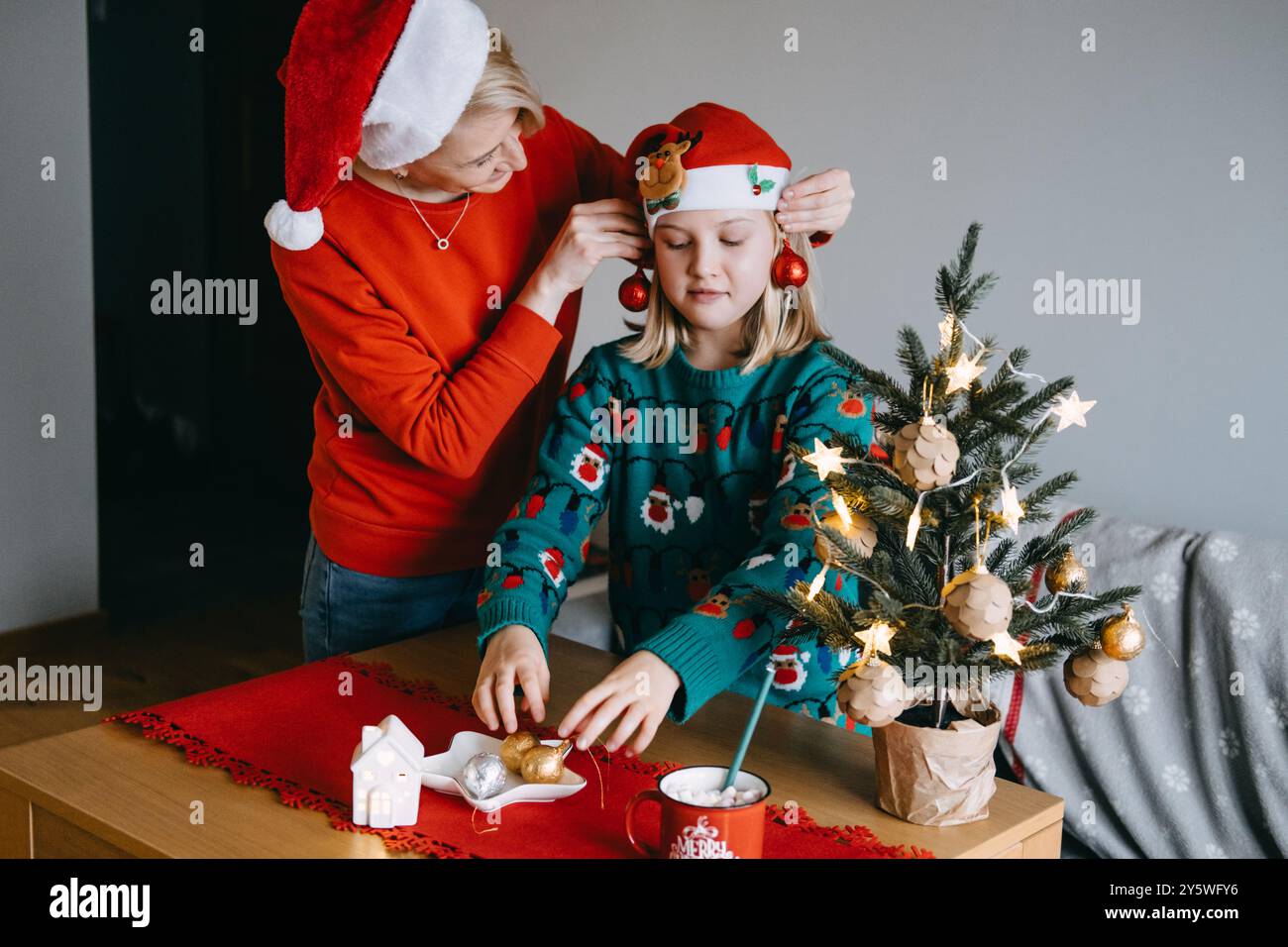 Mother and daughter decorating Christmas tree together, holiday bonding ...