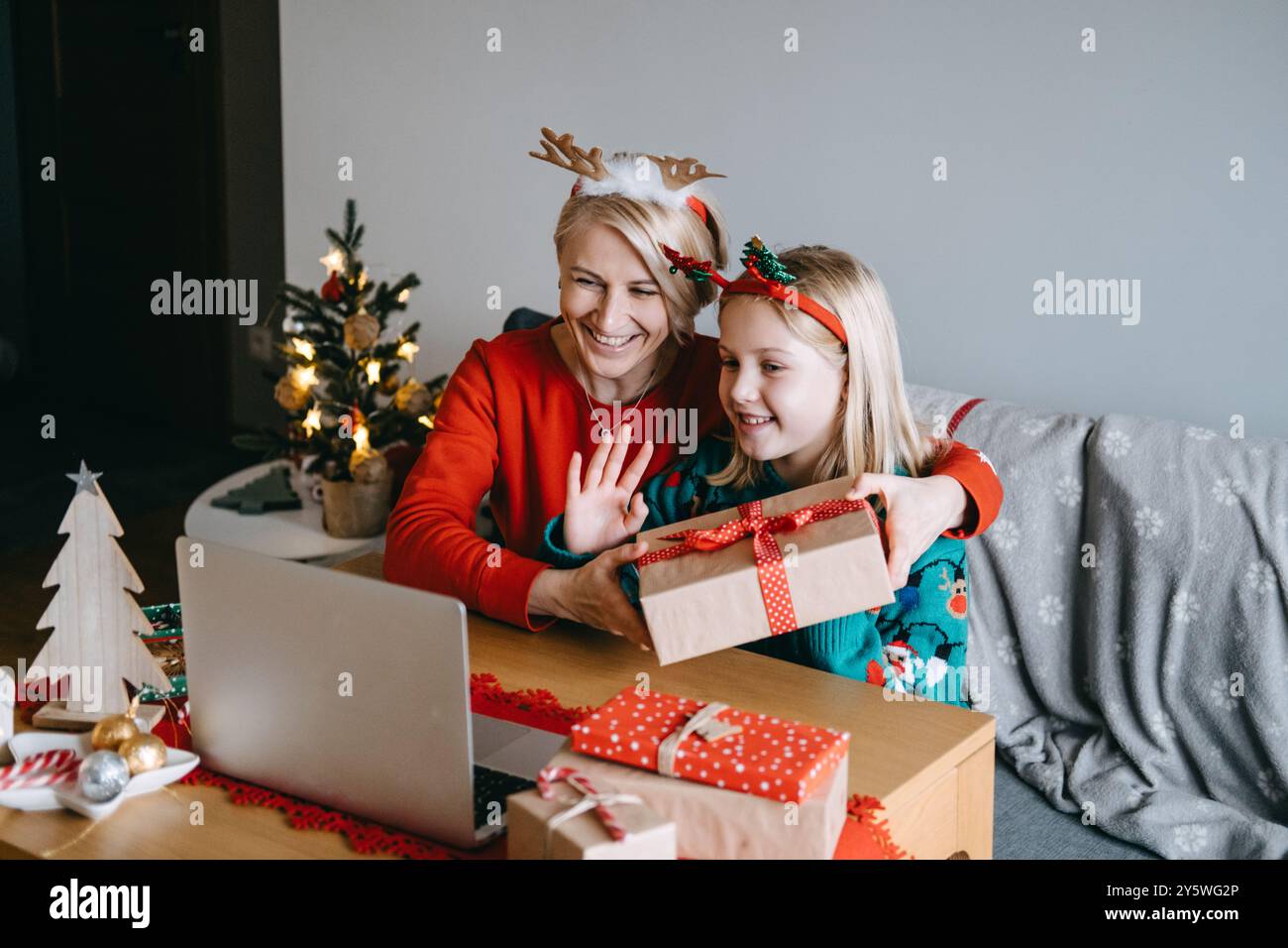 Mother and daughter celebrating Christmas virtually with loved ones. Virtual celebrations ...